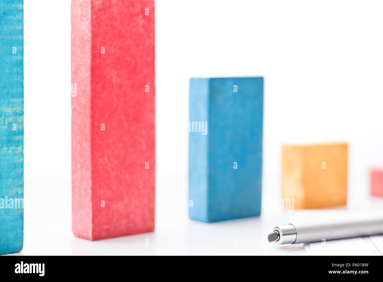 A silver pen and four colourful blocks used as progress bars on a white ...