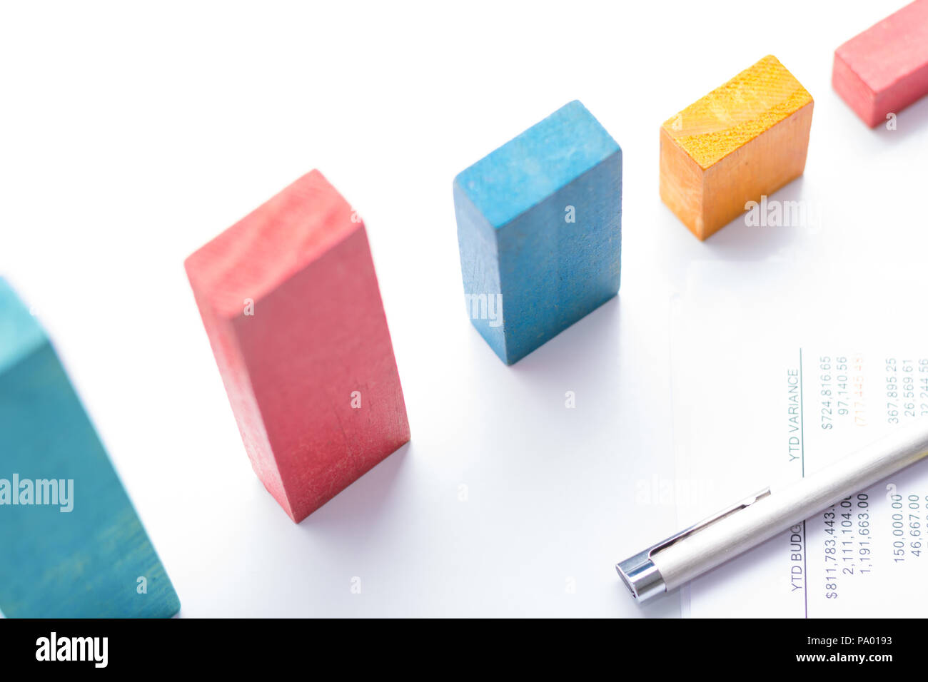 A silver pen, financial report, and four colourful blocks used as ...
