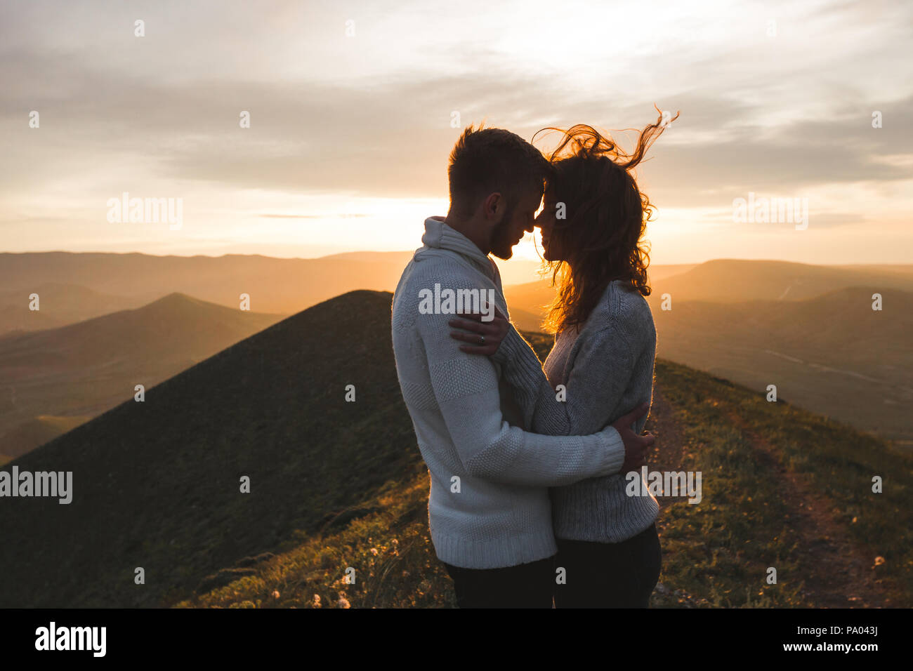 Happy couple hugging and kissing at sunset witn amazing mountain view ...