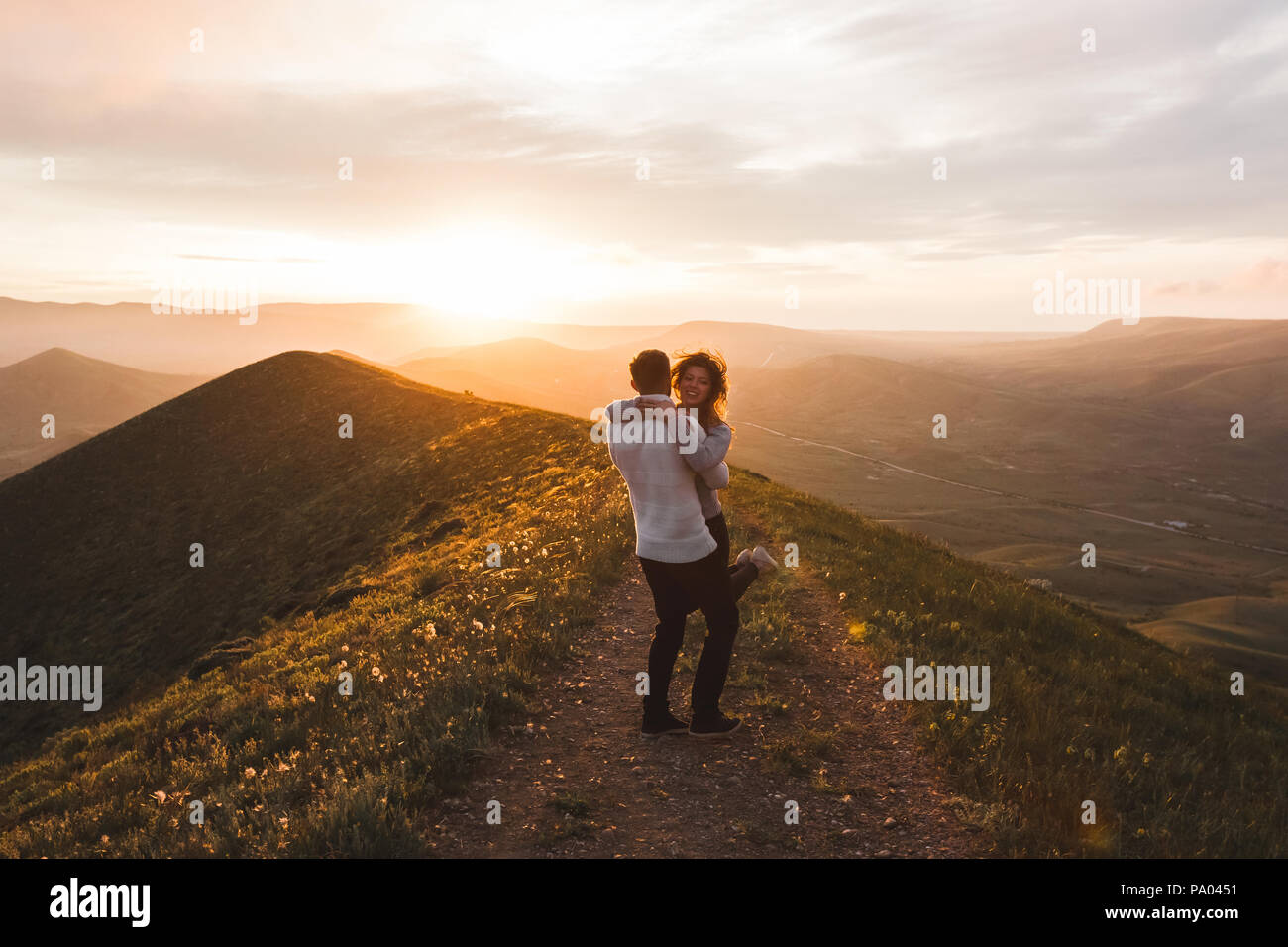 Happy couple hugging and kissing at sunset witn amazing mountain view ...