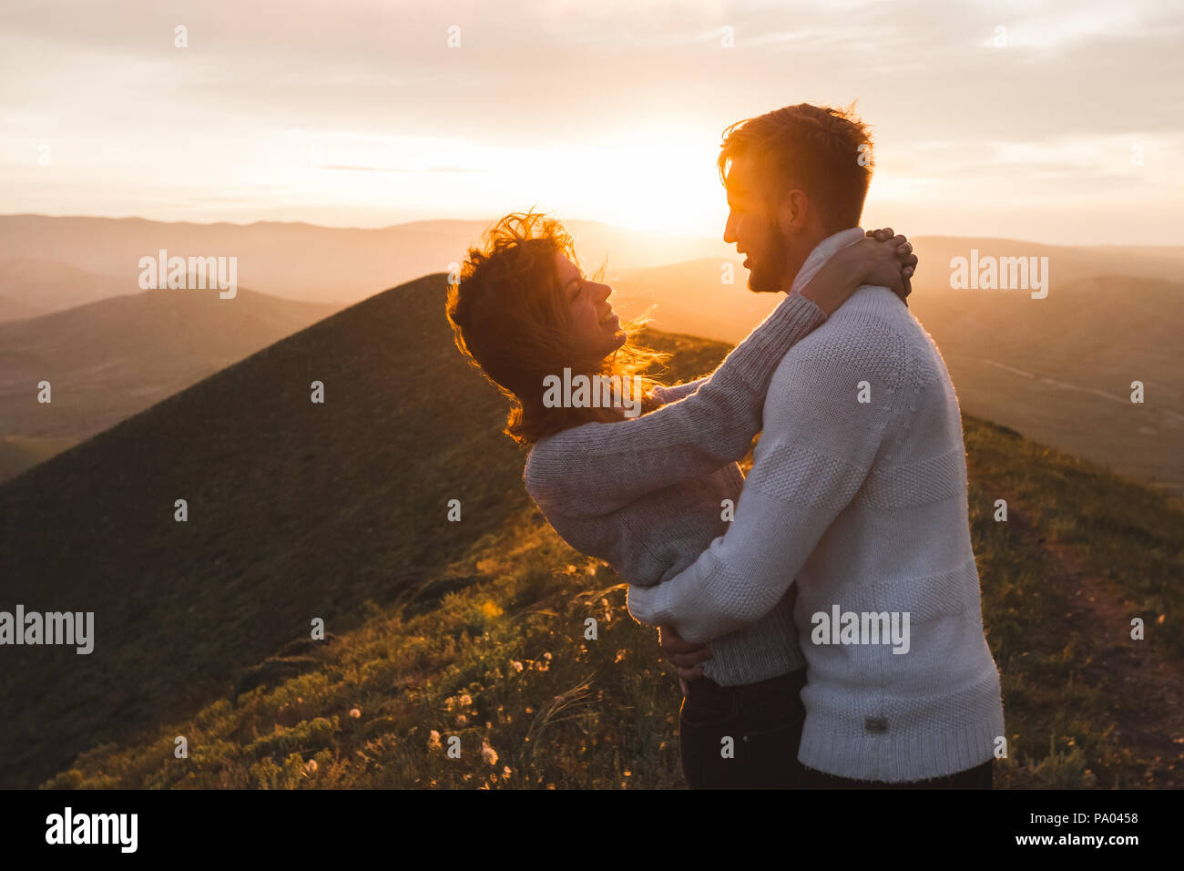 Happy couple hugging and kissing at sunset witn amazing mountain view ...