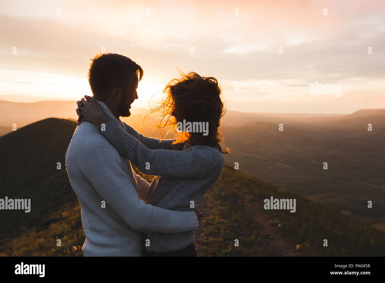 Happy couple hugging and kissing at sunset witn amazing mountain view ...