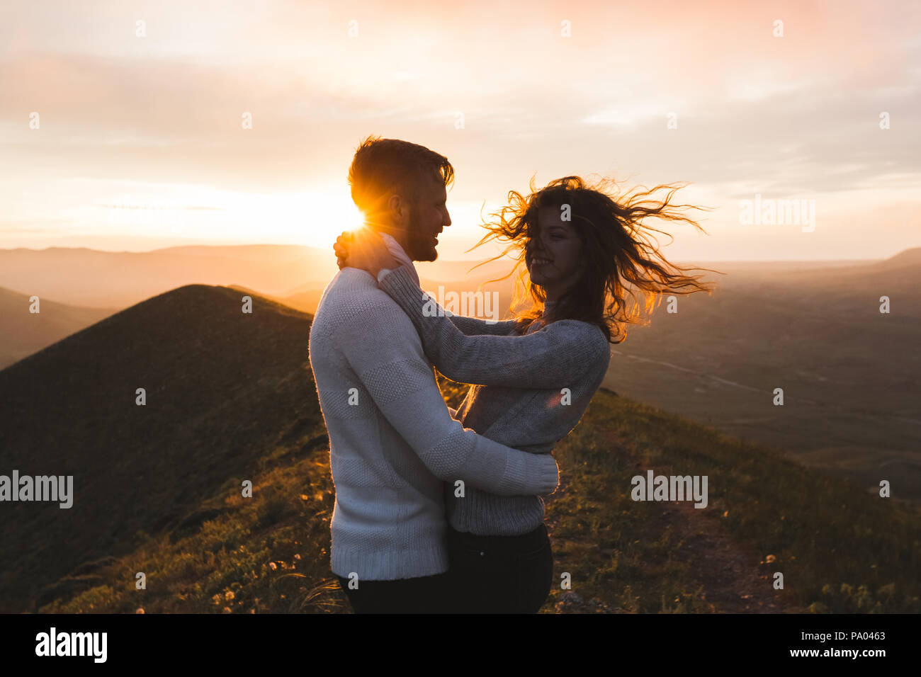 Happy couple hugging and kissing at sunset witn amazing mountain view ...
