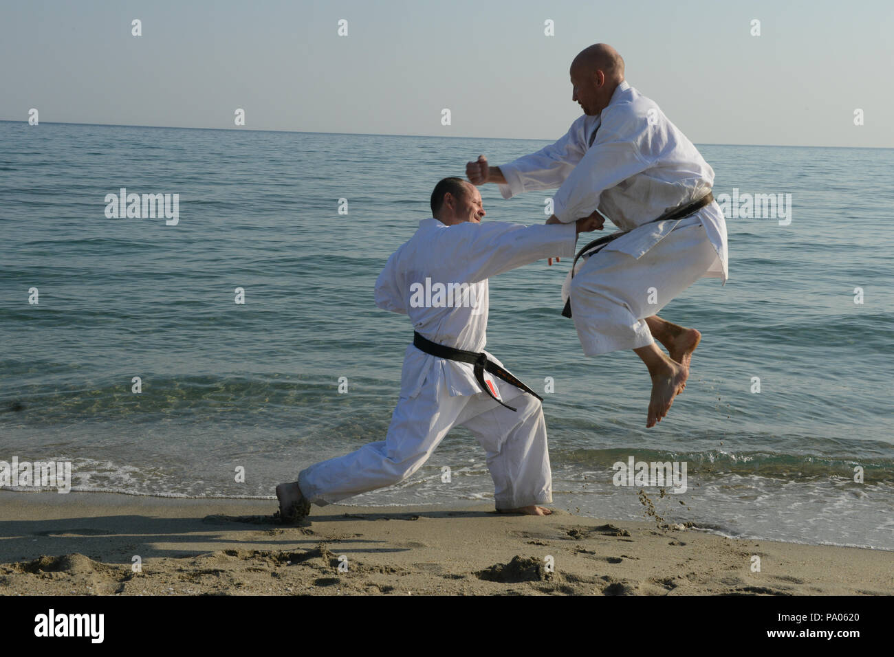 Two karate masters in a show fight at the beach Stock Photo - Alamy