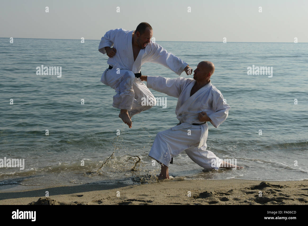 Two karate masters in a show fight at the beach Stock Photo - Alamy