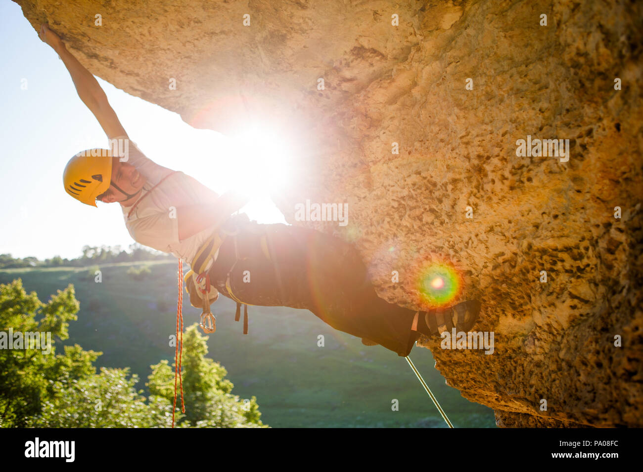 Image of man climber in helmet clambering up cliff Stock Photo - Alamy