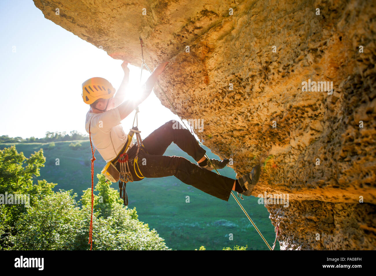Image of man climber in helmet clambering up cliff Stock Photo - Alamy