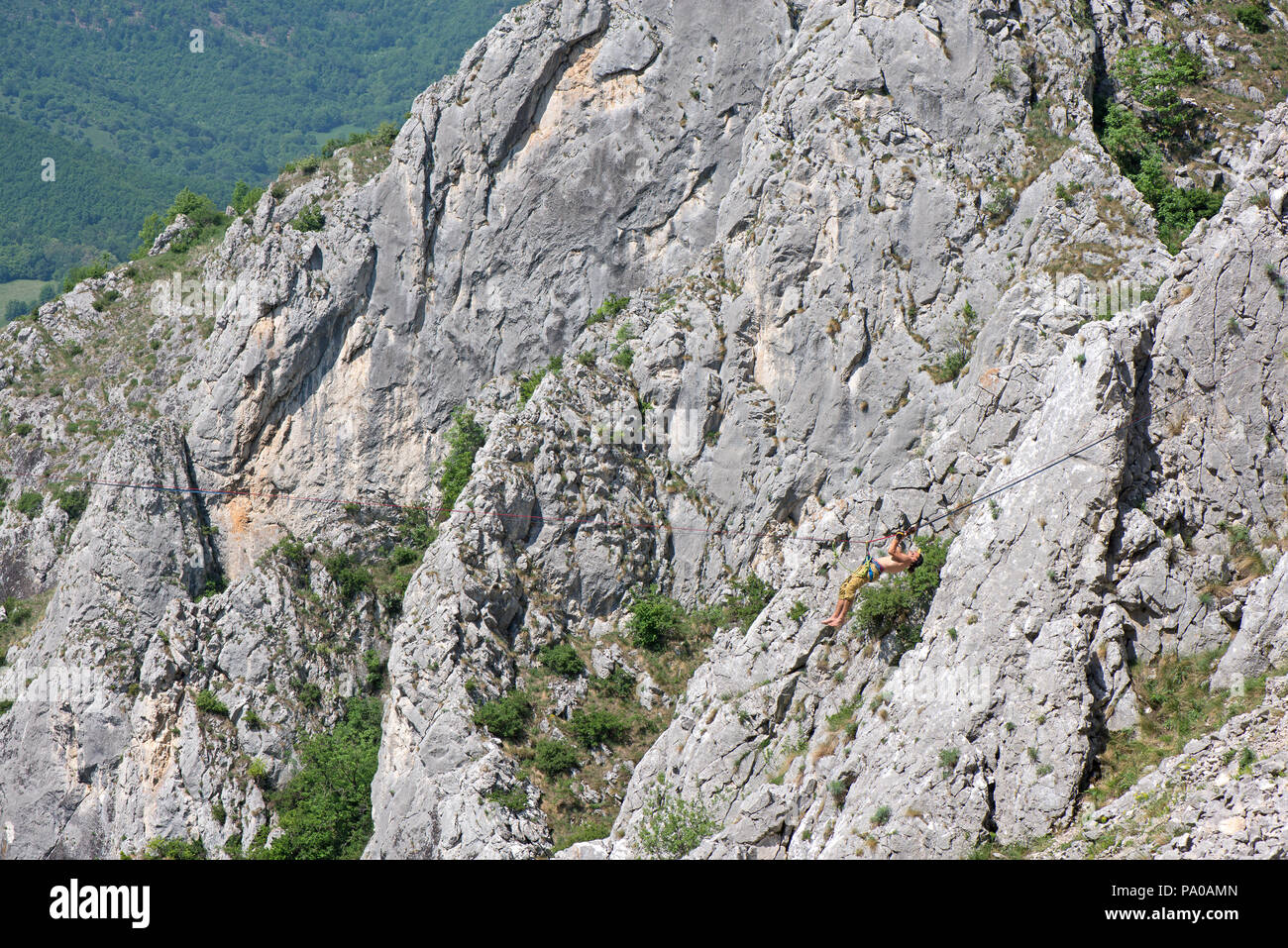 Fearless mountain climber with equipment hanging over dangerous ravine ...