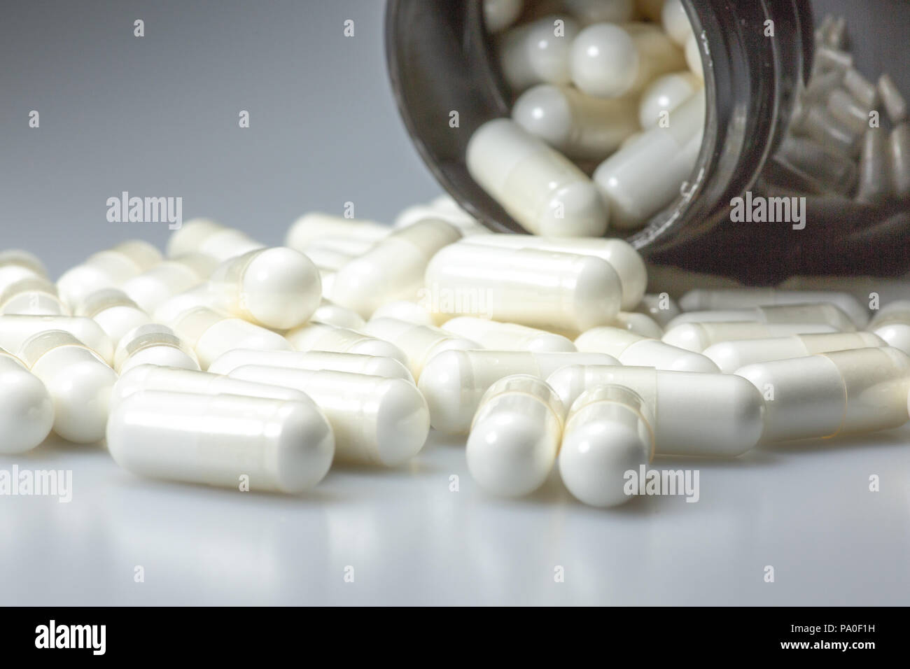 White large pills falling out of a large brown pill bottle Stock Photo ...