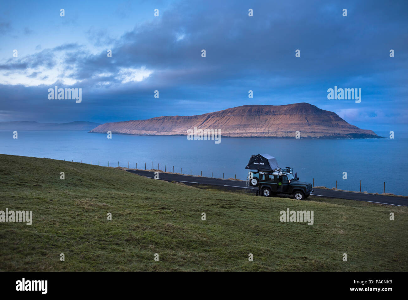 Side view of 4x4 car driving along coastline, Faroe Islands, Denmark ...