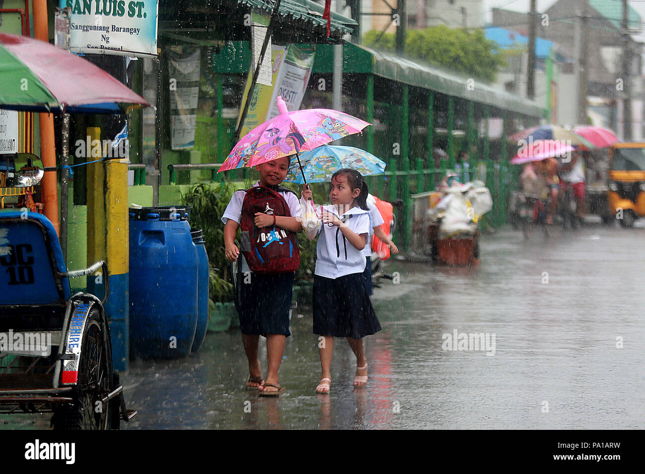 Bulacan, Philippines. 20th July, 2018. Students share an umbrella in ...