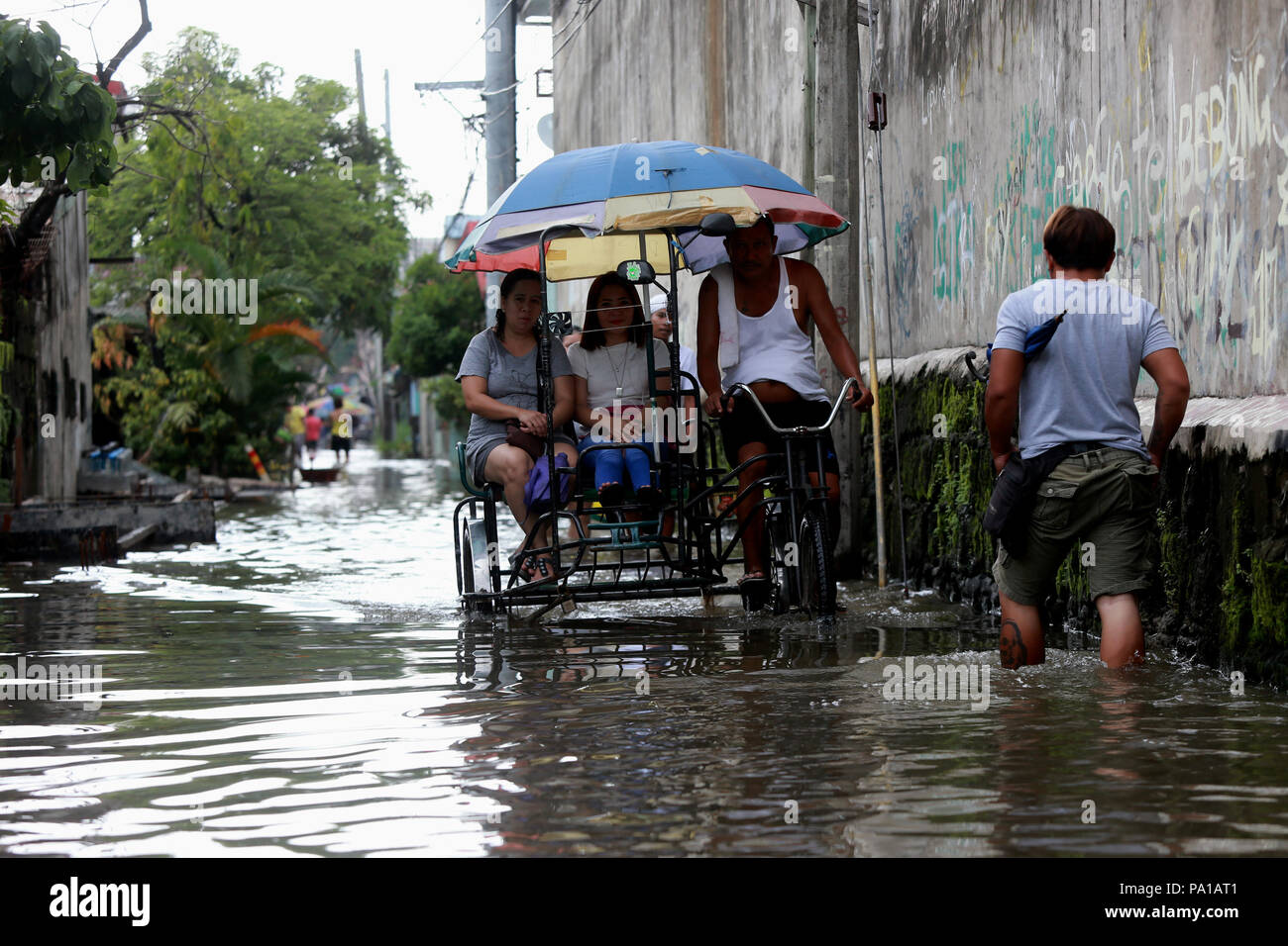 Bulacan, Philippines. 20th July, 2018. Residents on a rickshaw move in ...