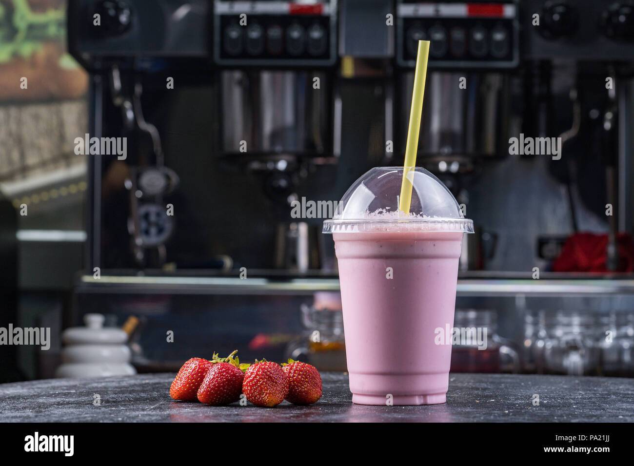 Strawberry milk shake to take away with straw on a dark background ...