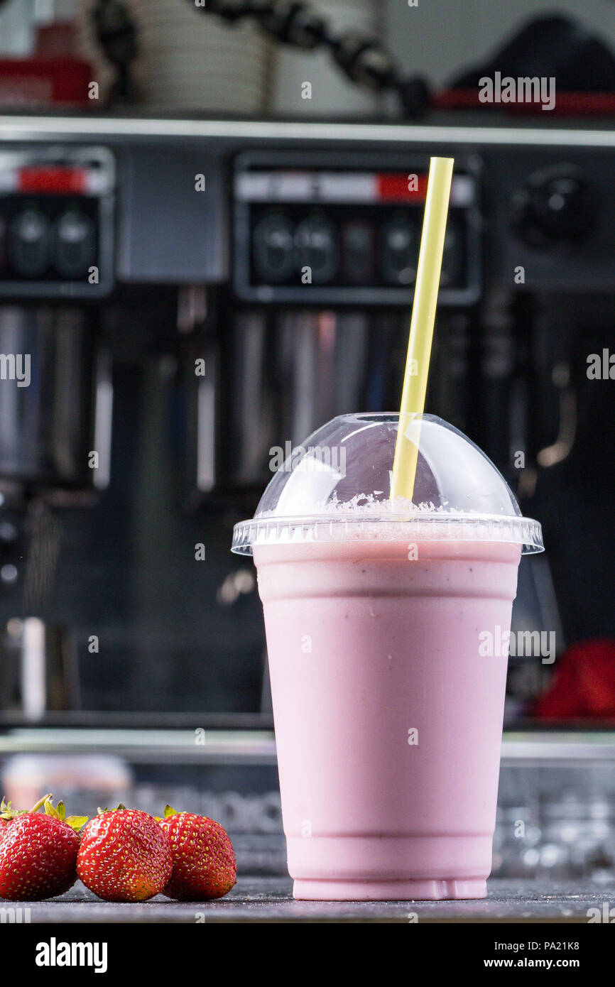 Strawberry milk shake to take away with straw on a dark background ...