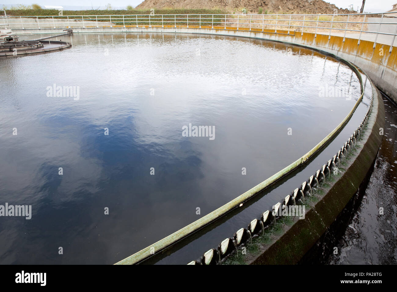 Treated wastewater flows over weirs in a wastewater treatment plant ...