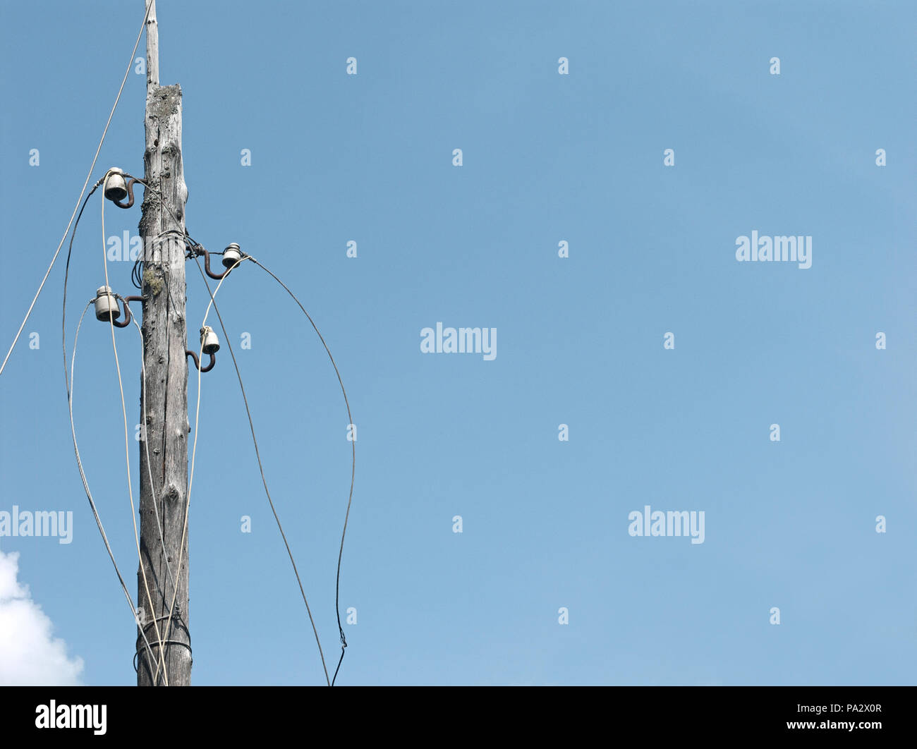 Electric post with disconnected wires against the blue sky, horizontal ...