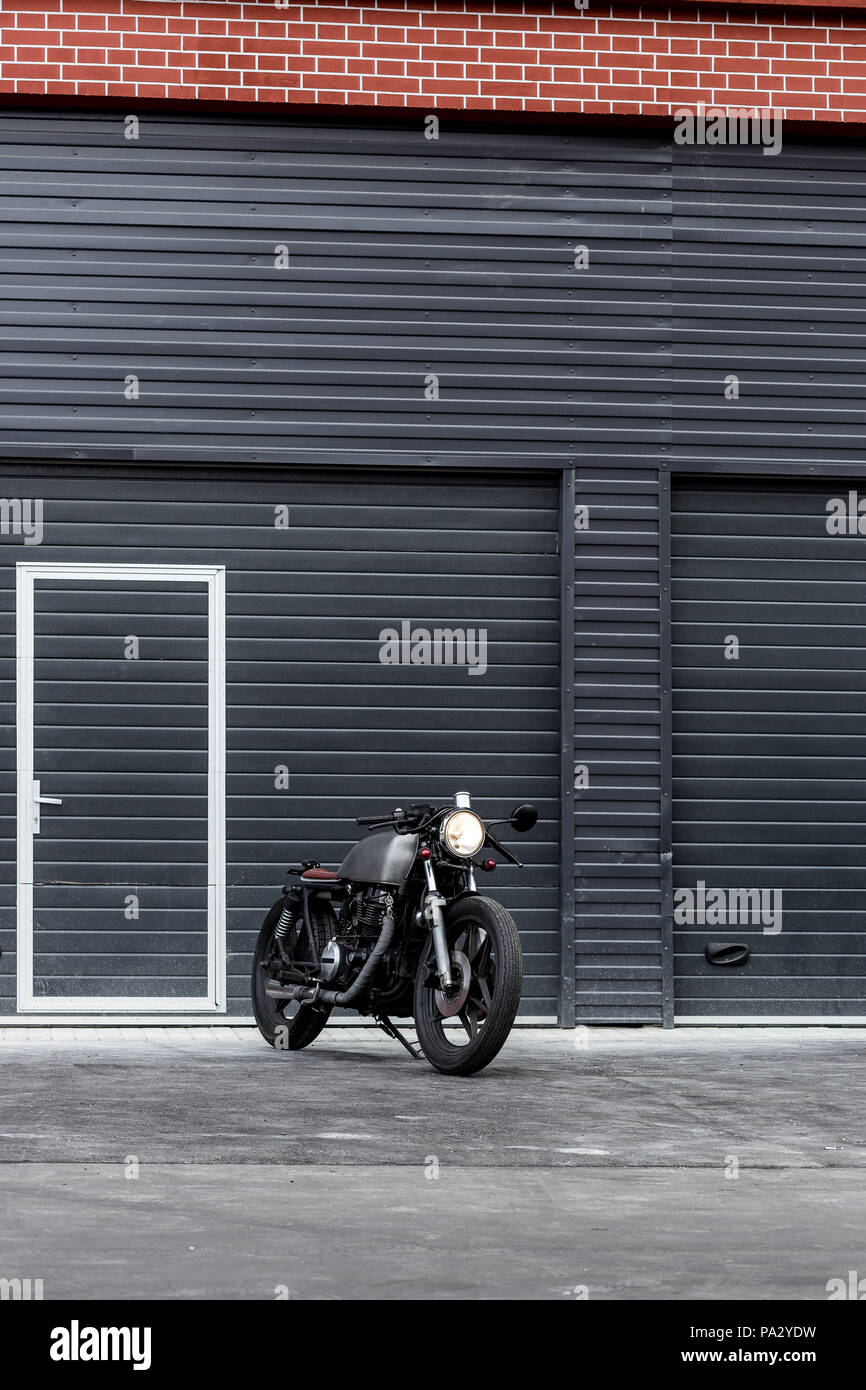 Custom motorcycle parking near dark industrial building. Everything is ...