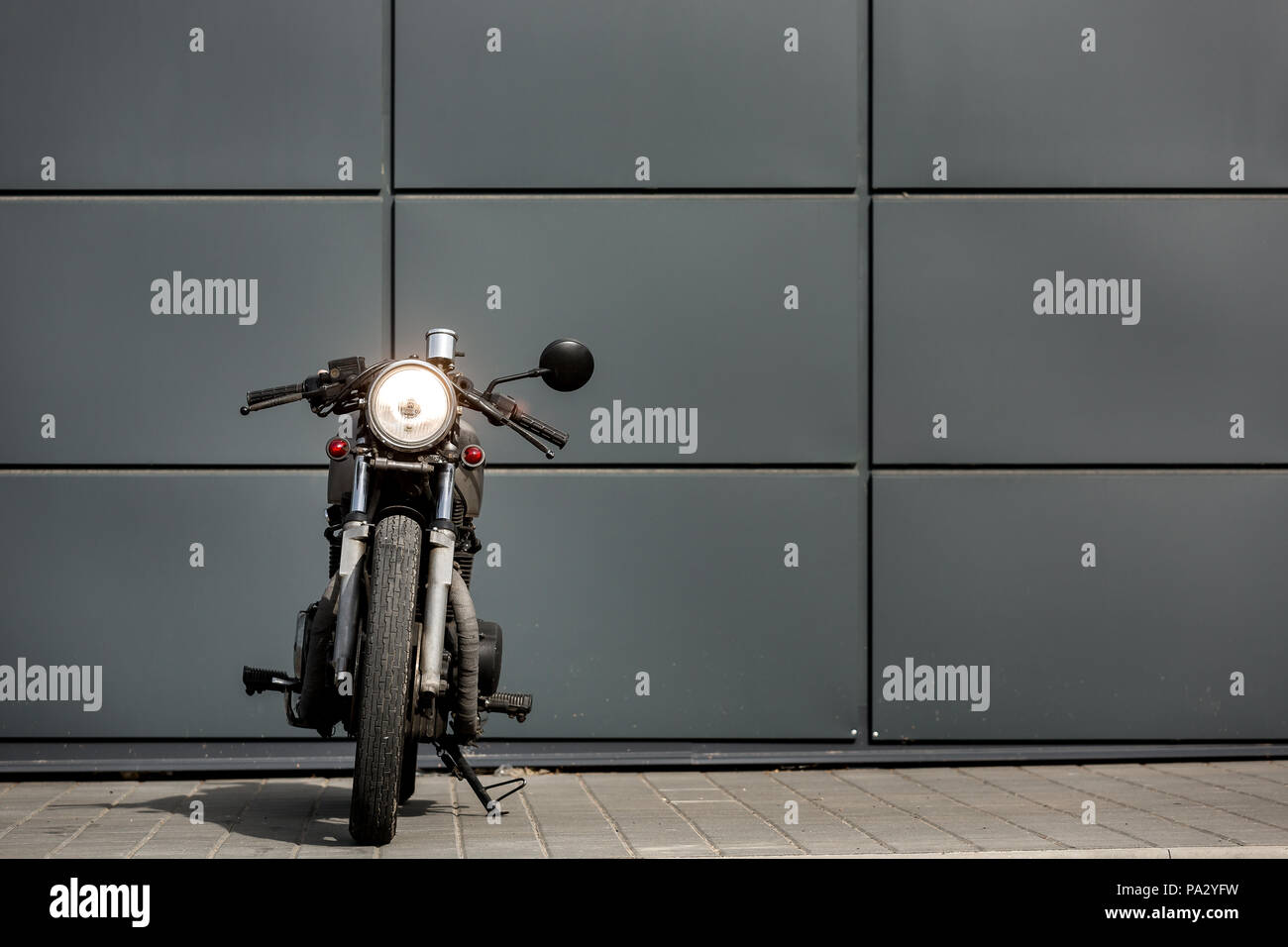 Custom motorcycle parking near gray wall of industrial building ...