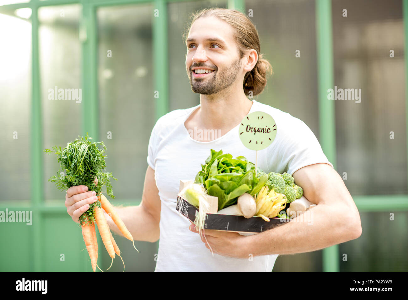 Portrait of a happy vegetarian man holding box full of fresh raw ...