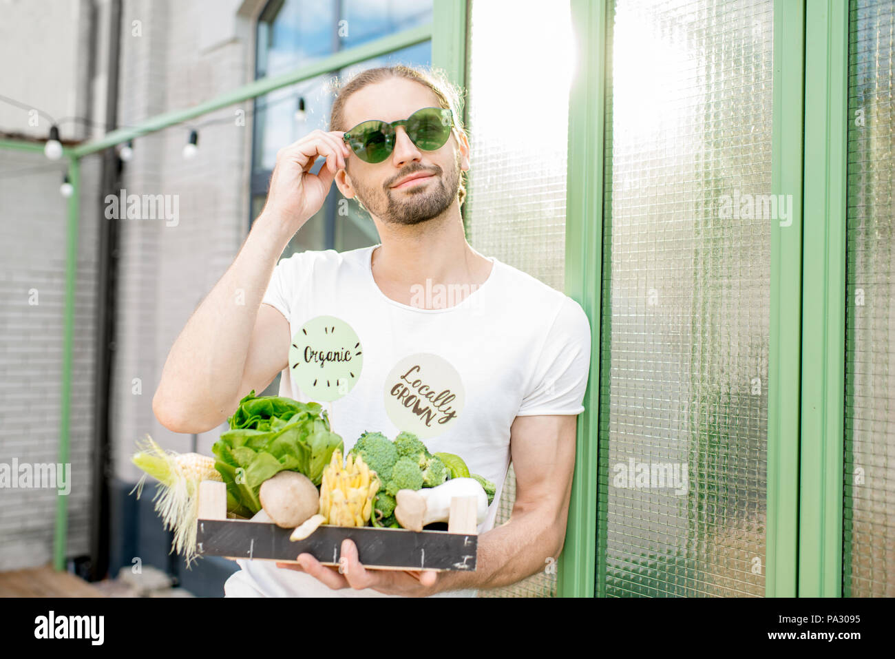 Portrait of a handsome vegetarian man standing with box full of organic ...
