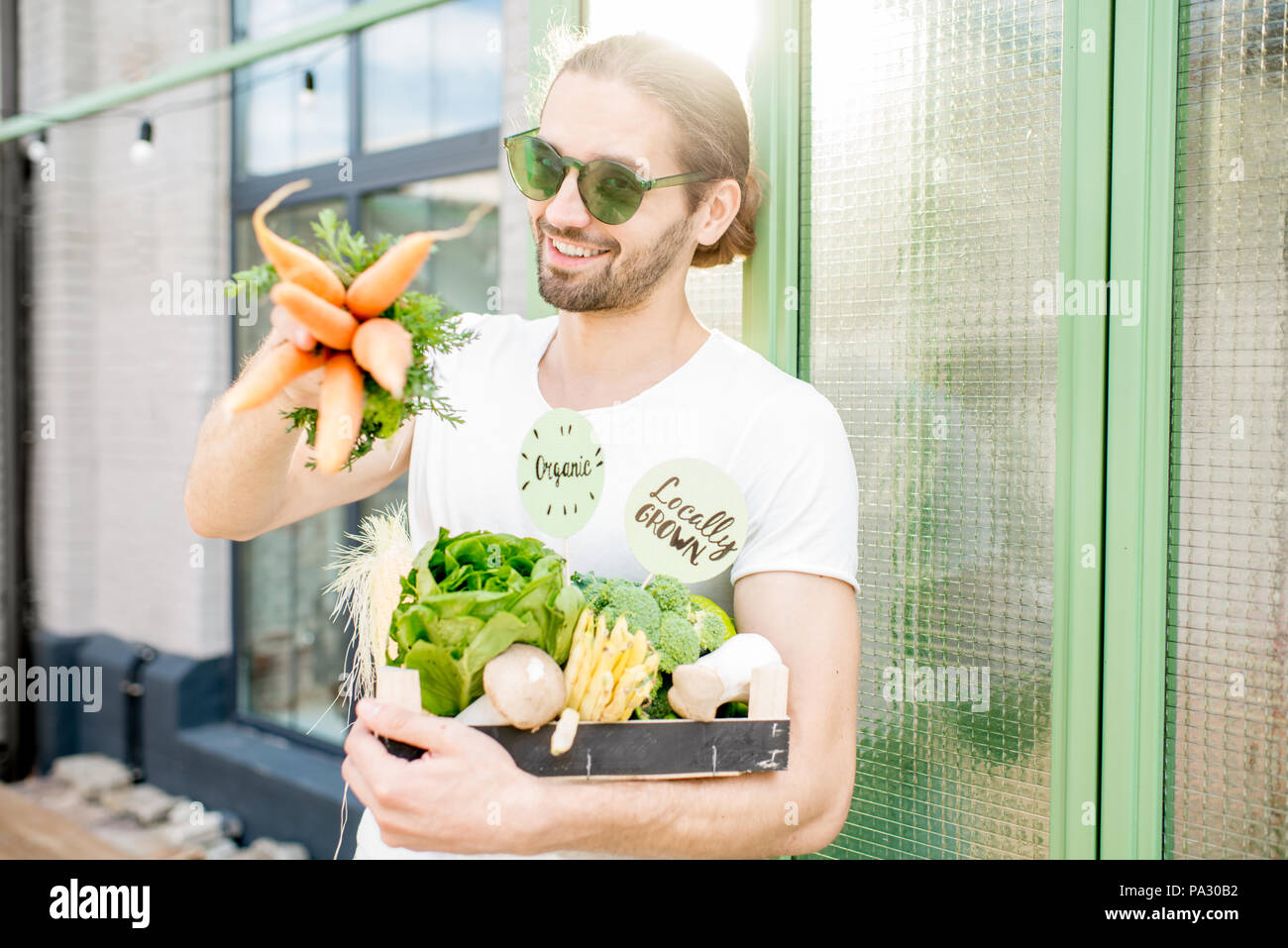 Funny portrait of a handsome vegetarian man standing with bunch of ...