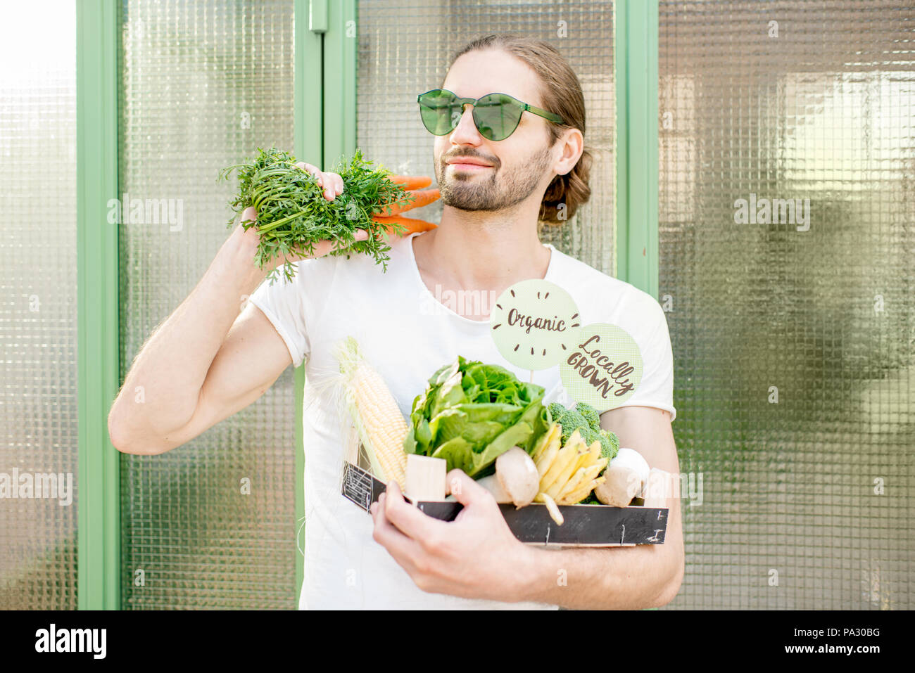 Portrait of a handsome vegetarian man standing with box full of organic ...