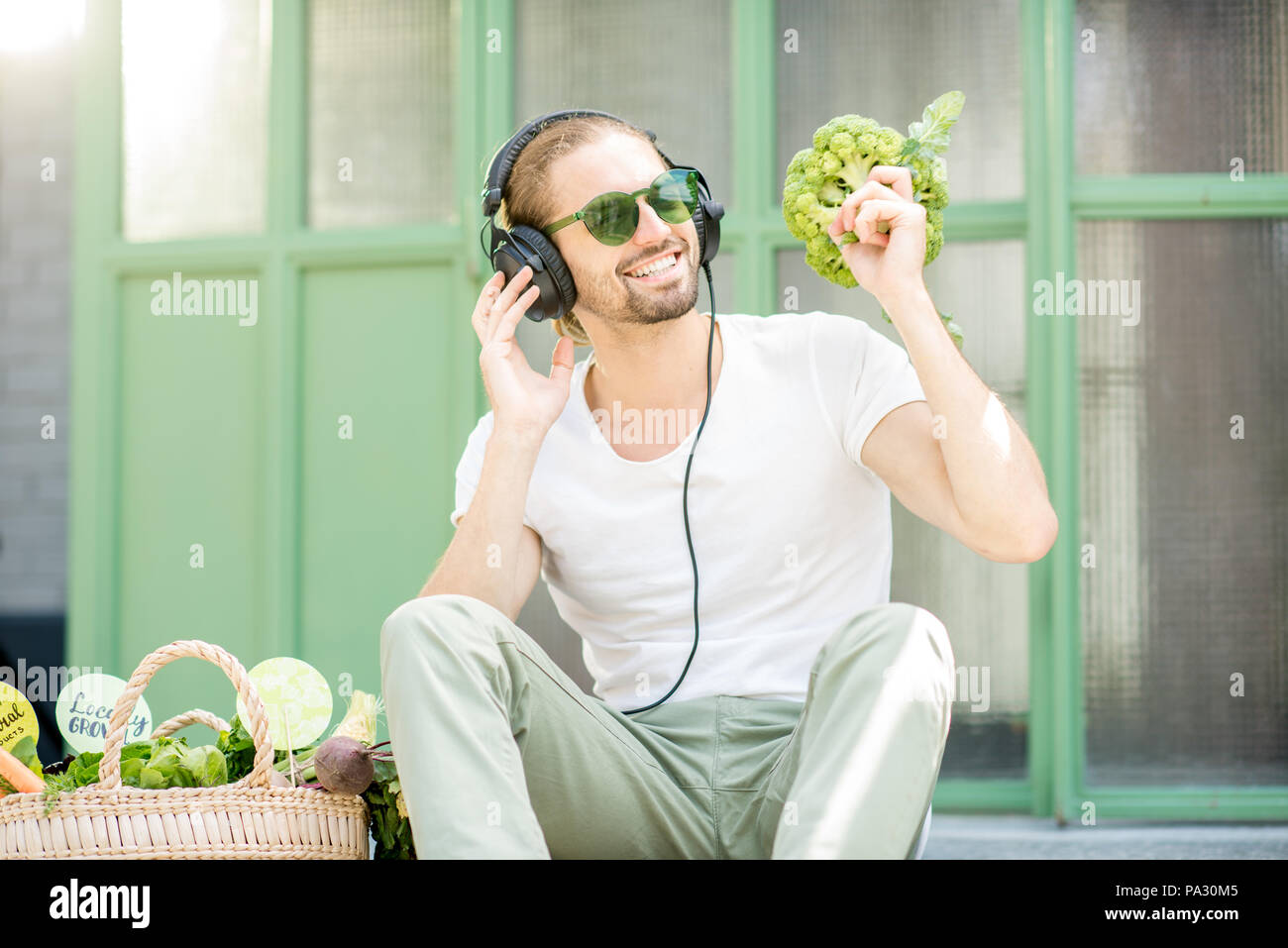 Funny portrait of a man listening to the music shaking with broccoli ...