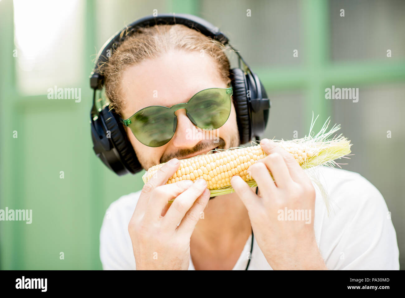 Funny musician playing harmonica with corn outdoors on the green ...