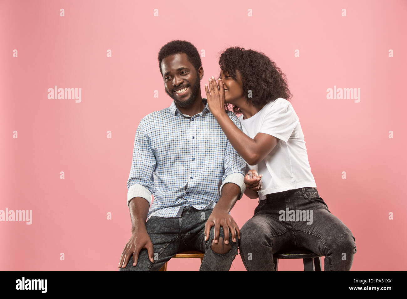 The young woman whispering a secret behind her hand to afro man Stock ...