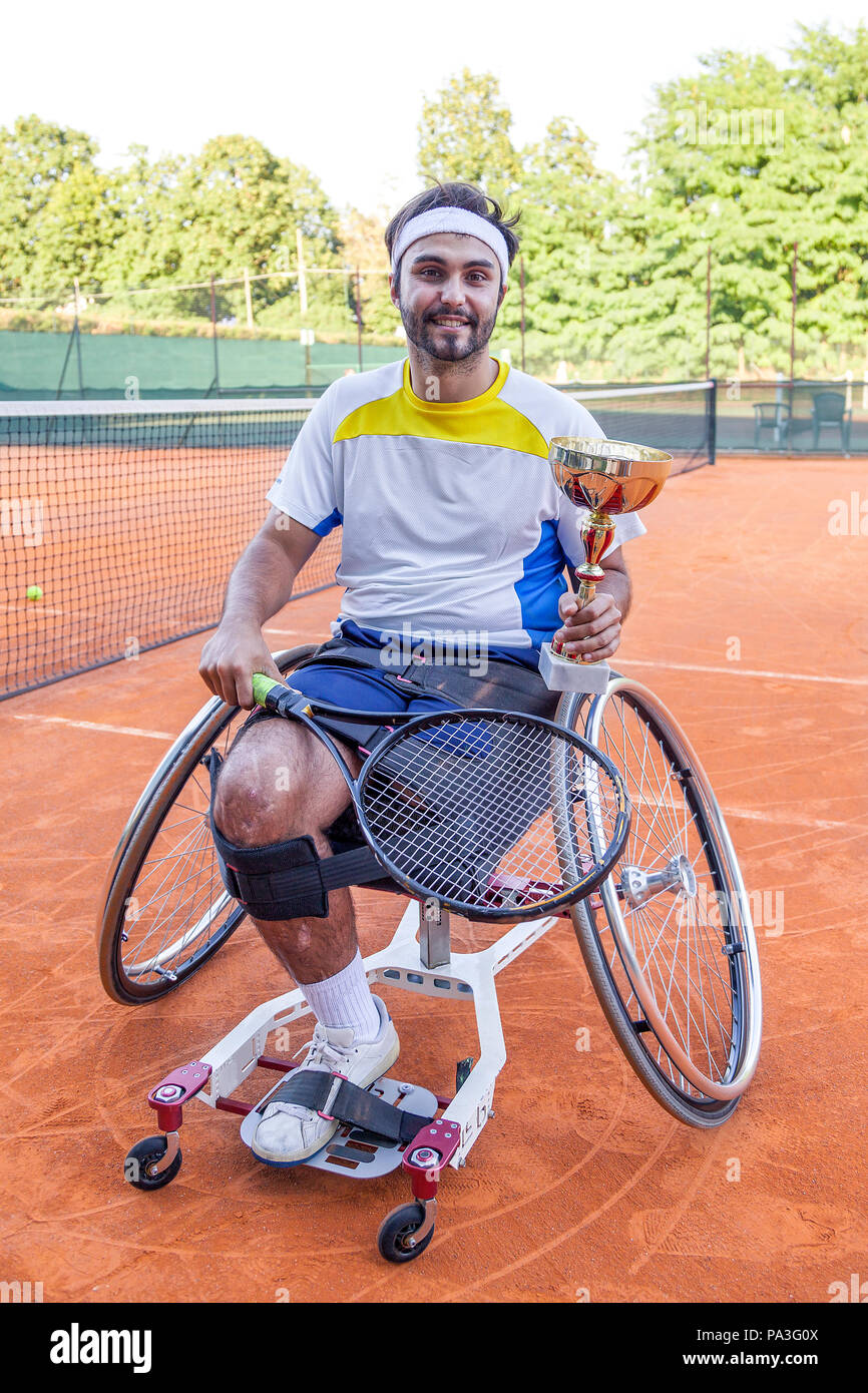 young disabled tennis player shows the cup after winning the outdoor ...