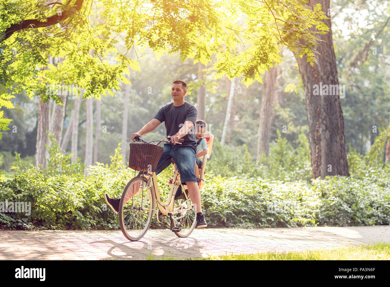 Smiling active father with kid on bicycles having fun in park. Family ...