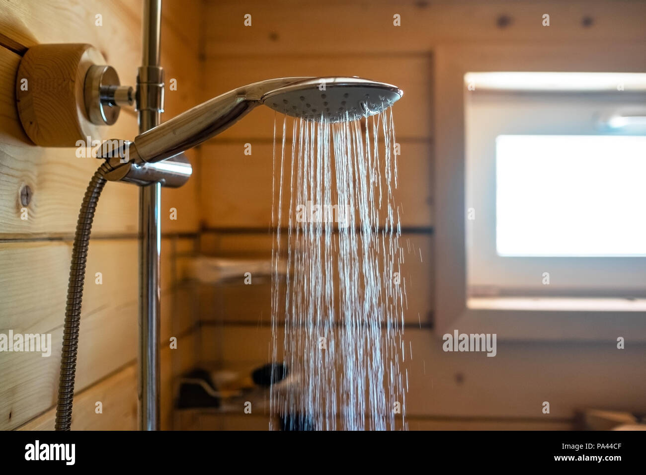 Shower head with flow of water closeup in wooden bathroom. Wasting of ...