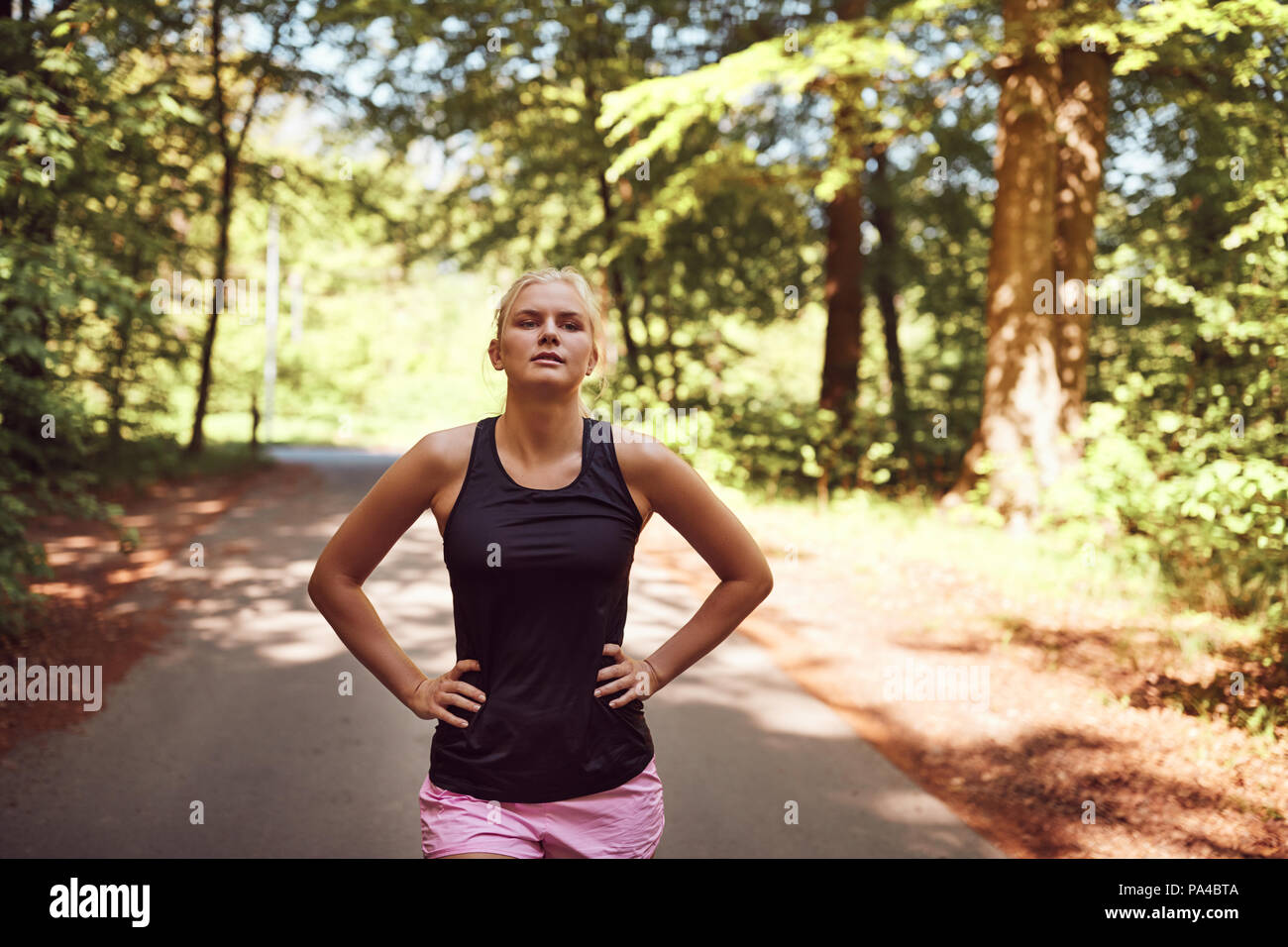 Fit young blonde woman in sportswear standing with her hands on her ...