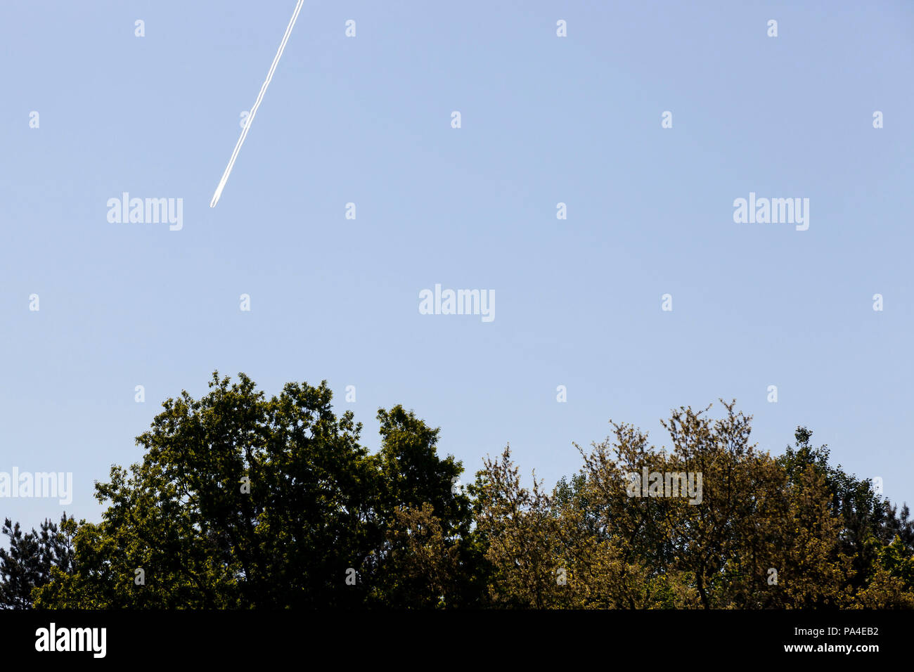 an inversion trail from a flying plane against a blue sky, sunny clear ...