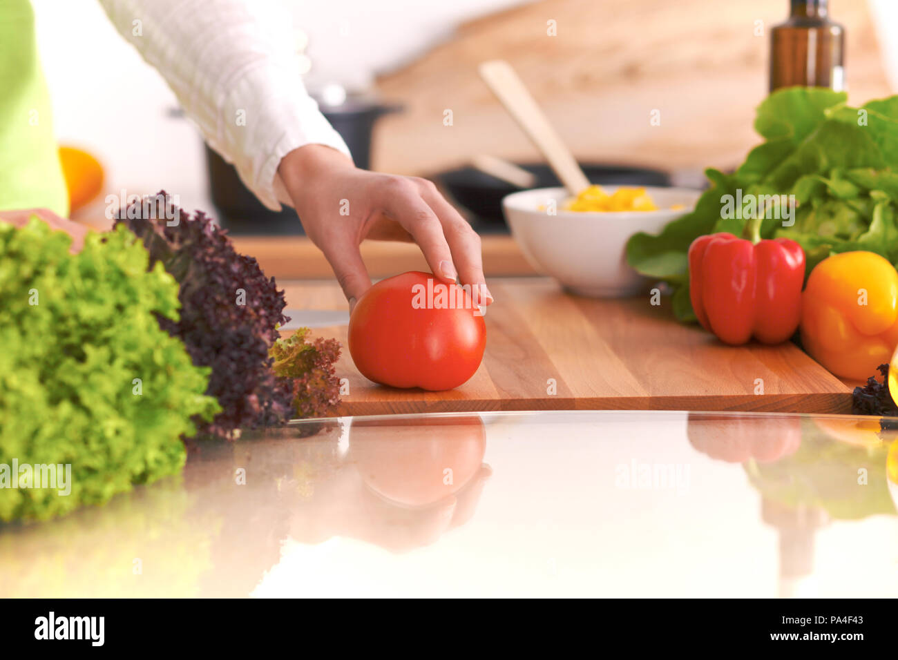 Close Up of human hands cooking vegetable salad in kitchen on the glass ...