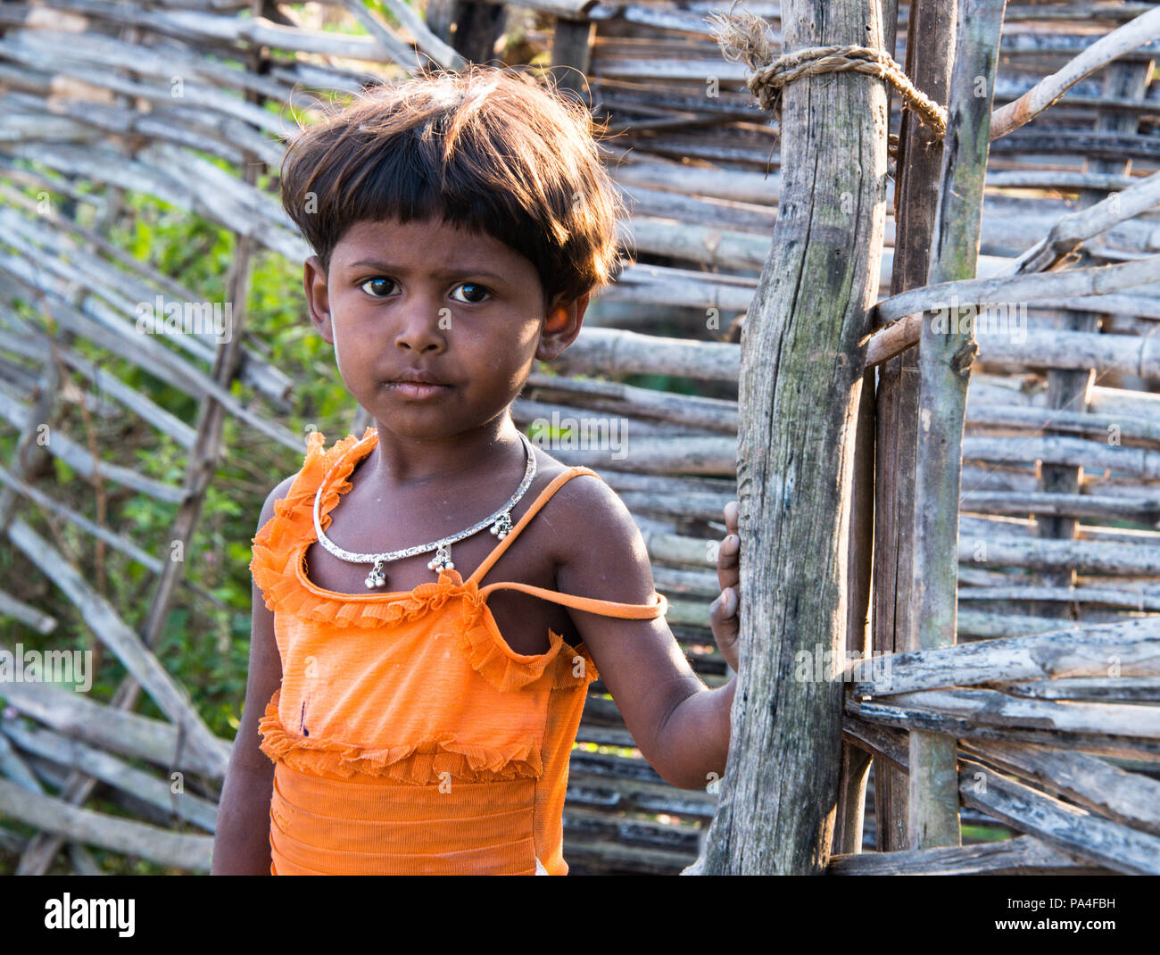 A local indian girl stands outside her house to see tourists walking by ...