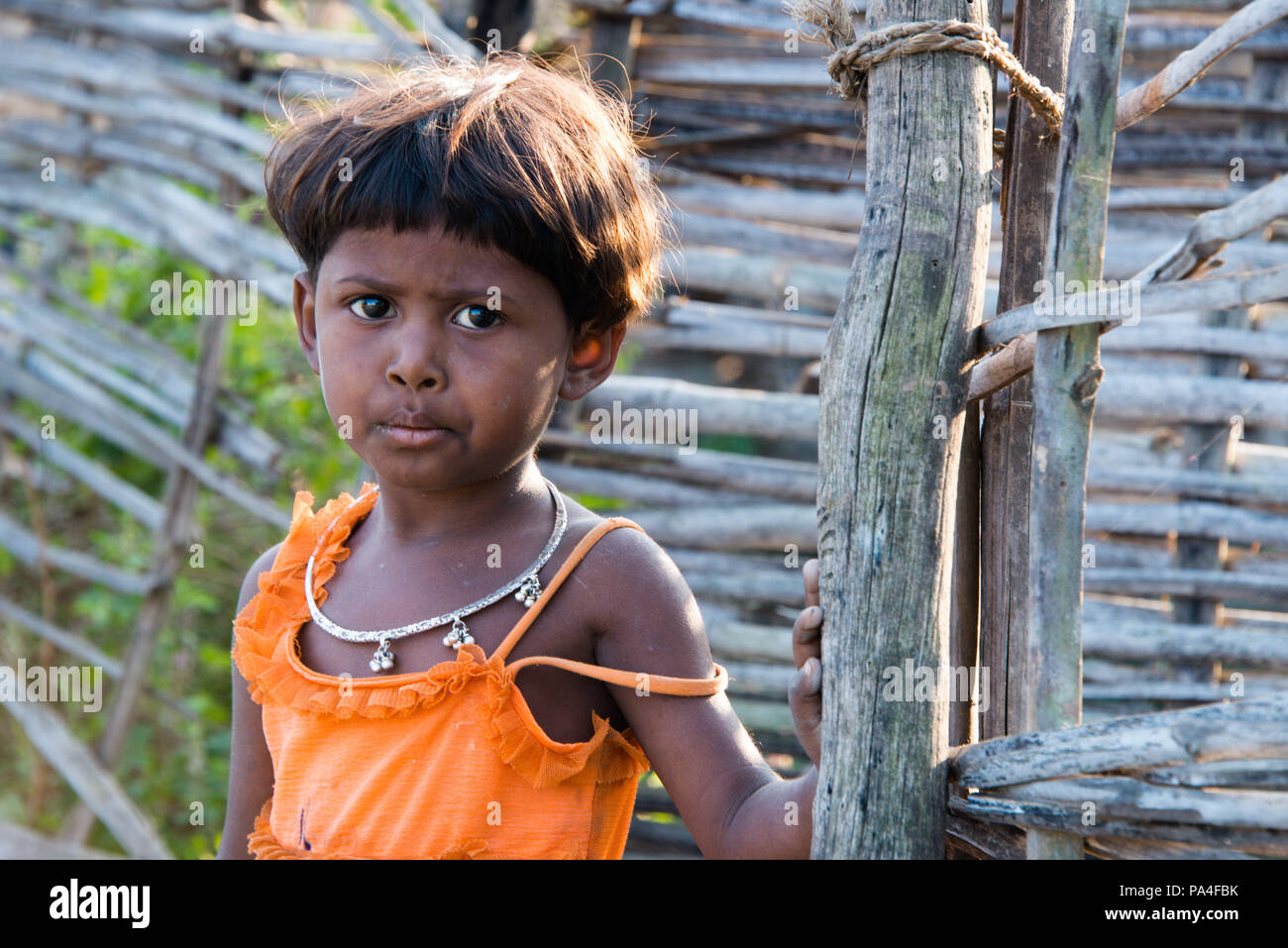 A local indian girl stands outside her house to see tourists walking by ...