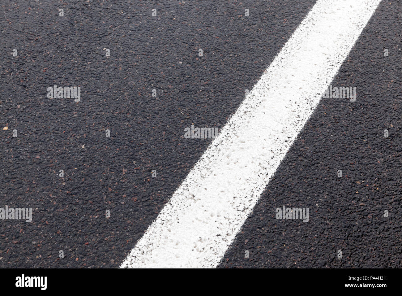 wet after the rain asphalt road with a diagonally drawn white line of ...