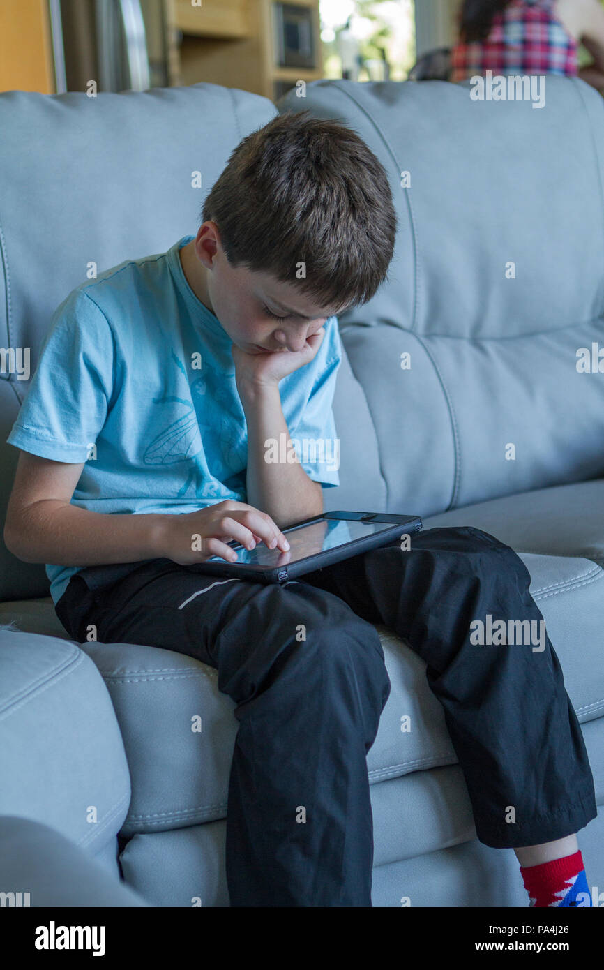 Teen age boy and his iPad, concentrating. Wearing blue shirt and on ...