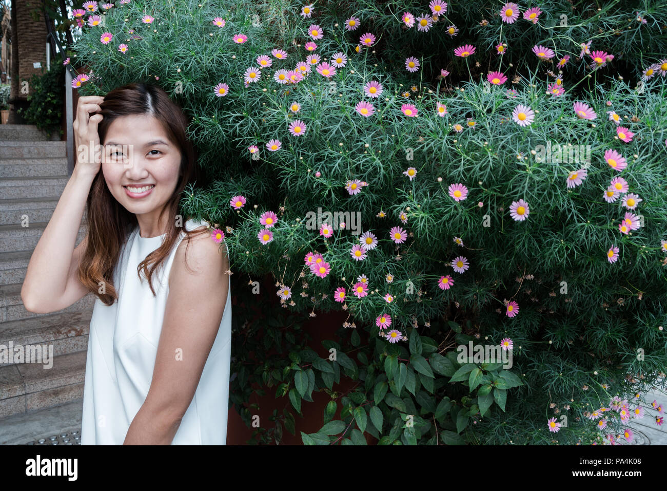 Portrait of beautiful and sweet Asian girl having fun with bushes of ...