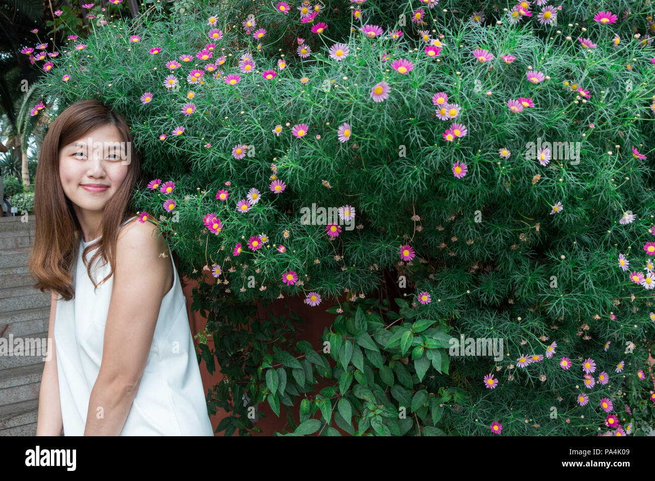 Portrait of beautiful and sweet Asian girl having fun with bushes of ...