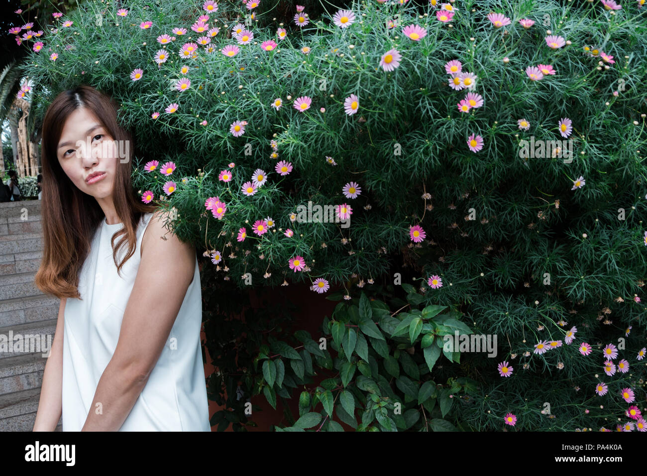 Portrait of beautiful and sweet Asian girl having fun with bushes of ...