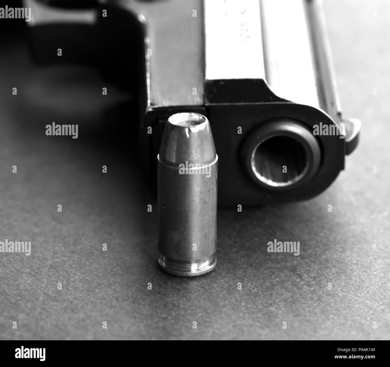 A single 40 caliber hollow point bullet standing next to the muzzle of ...