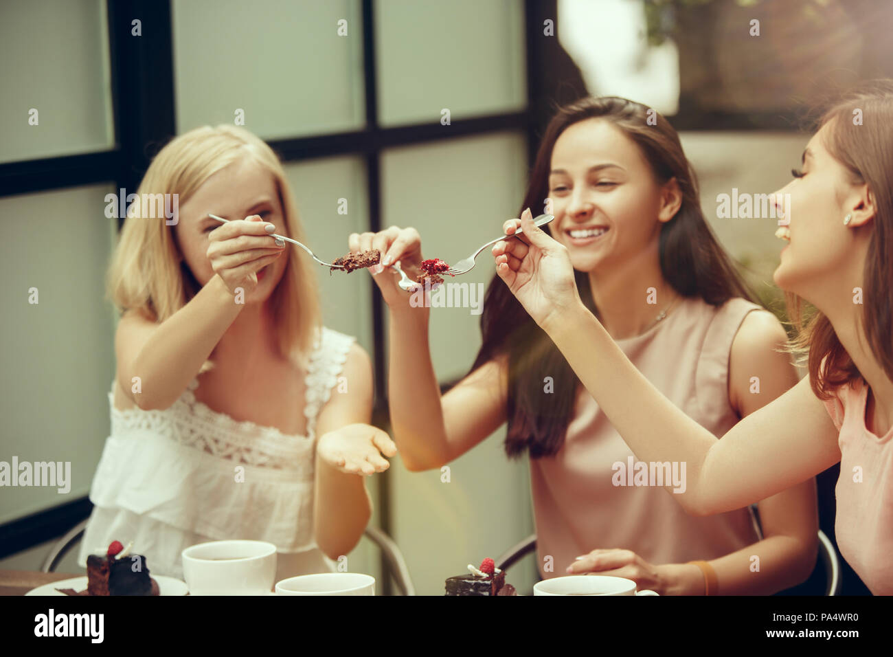 Two girl friends spend time together drinking coffee in the cafe ...