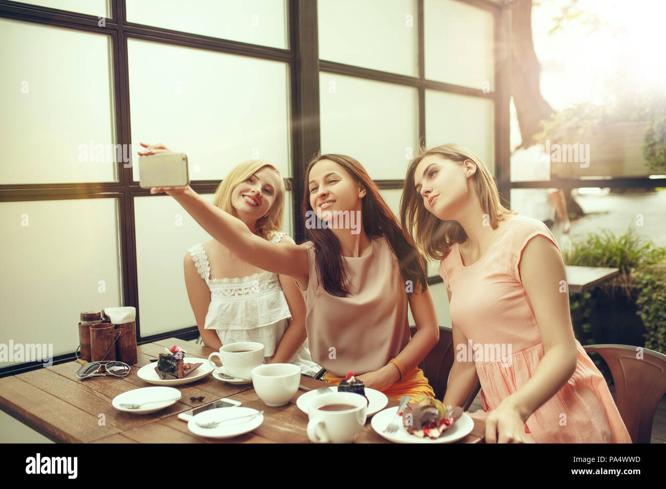 Two girl friends spend time together drinking coffee in the cafe ...