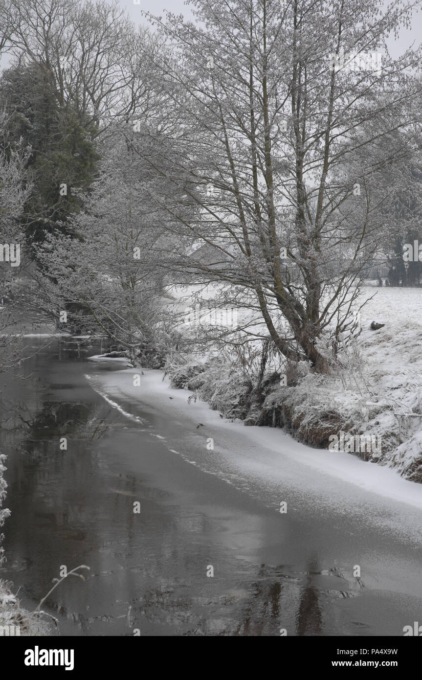 Snowy river scene with still and iced water and bare snowy trees Stock ...