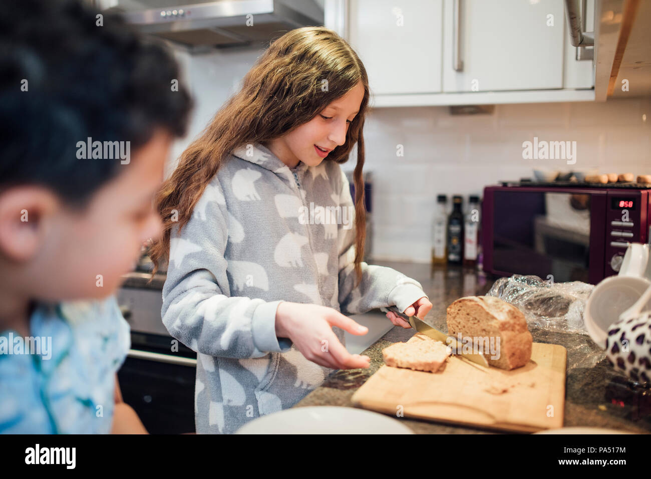 Little girl is taking a slice of bread to make toast for breakfast ...