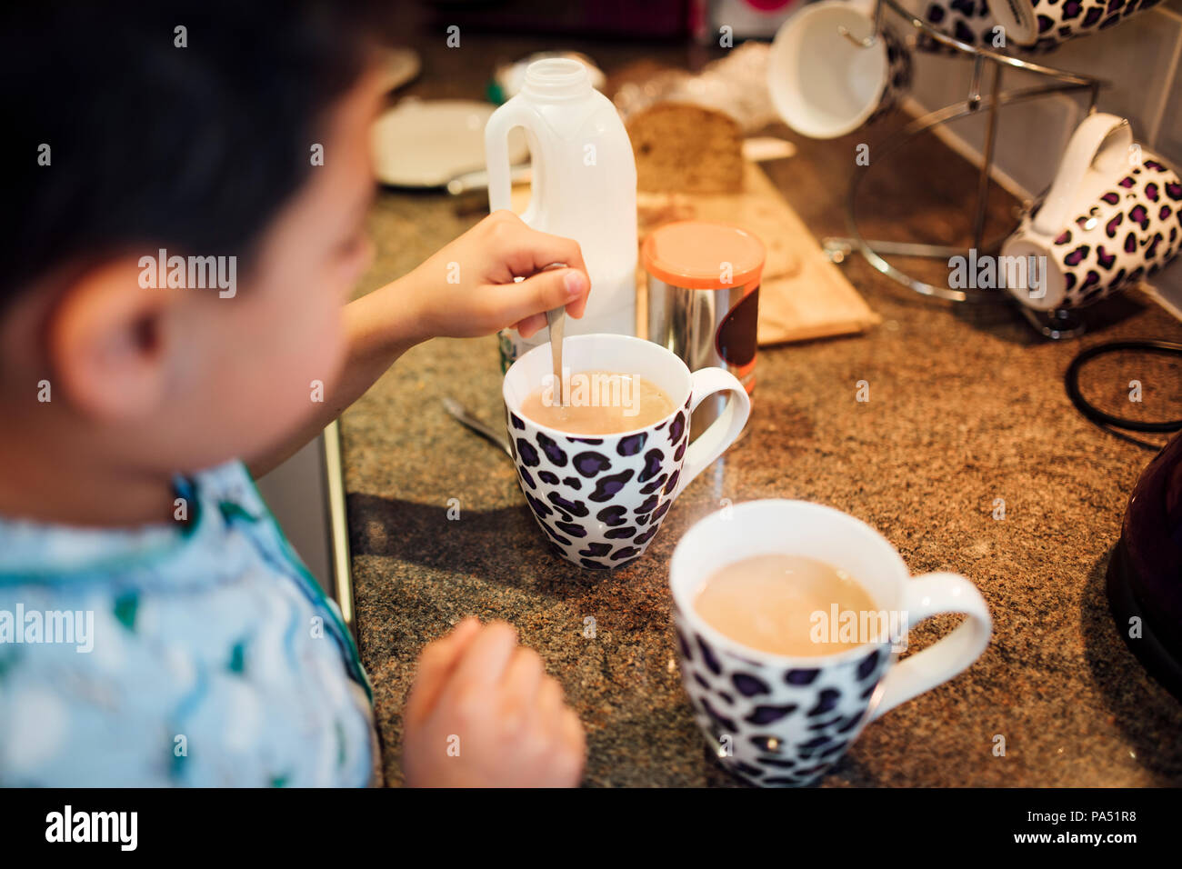 Little boy is helping his dad make tea in the morning. He is mixing the ...