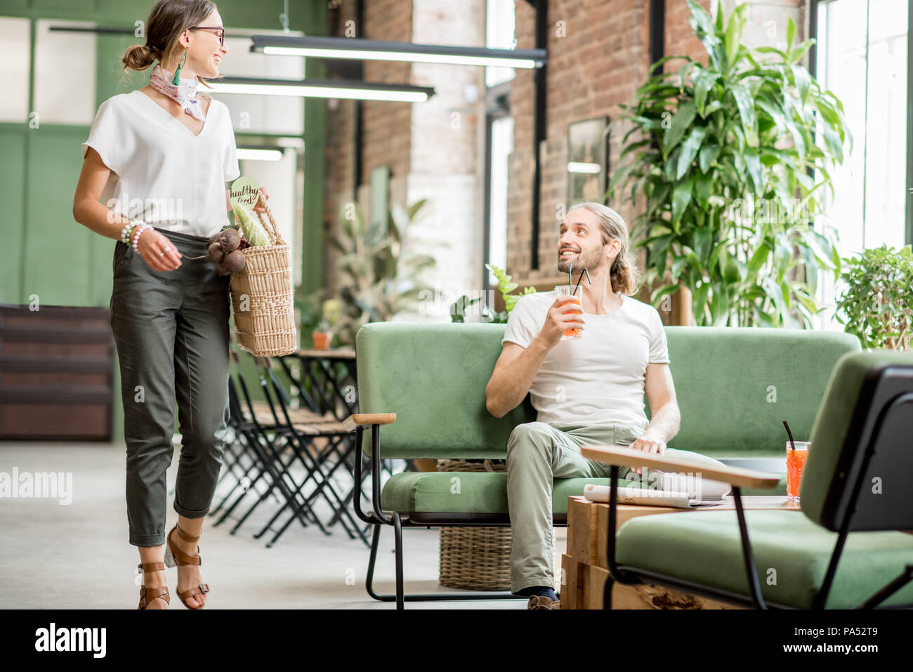 Woman walking through the man sitting on the sofa indoors at the ...