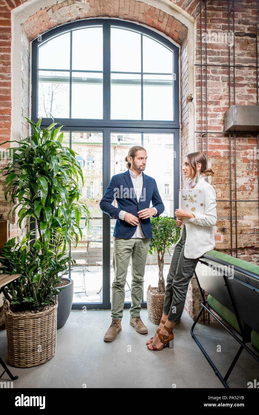 Business people having a conversation standing near the window in the ...